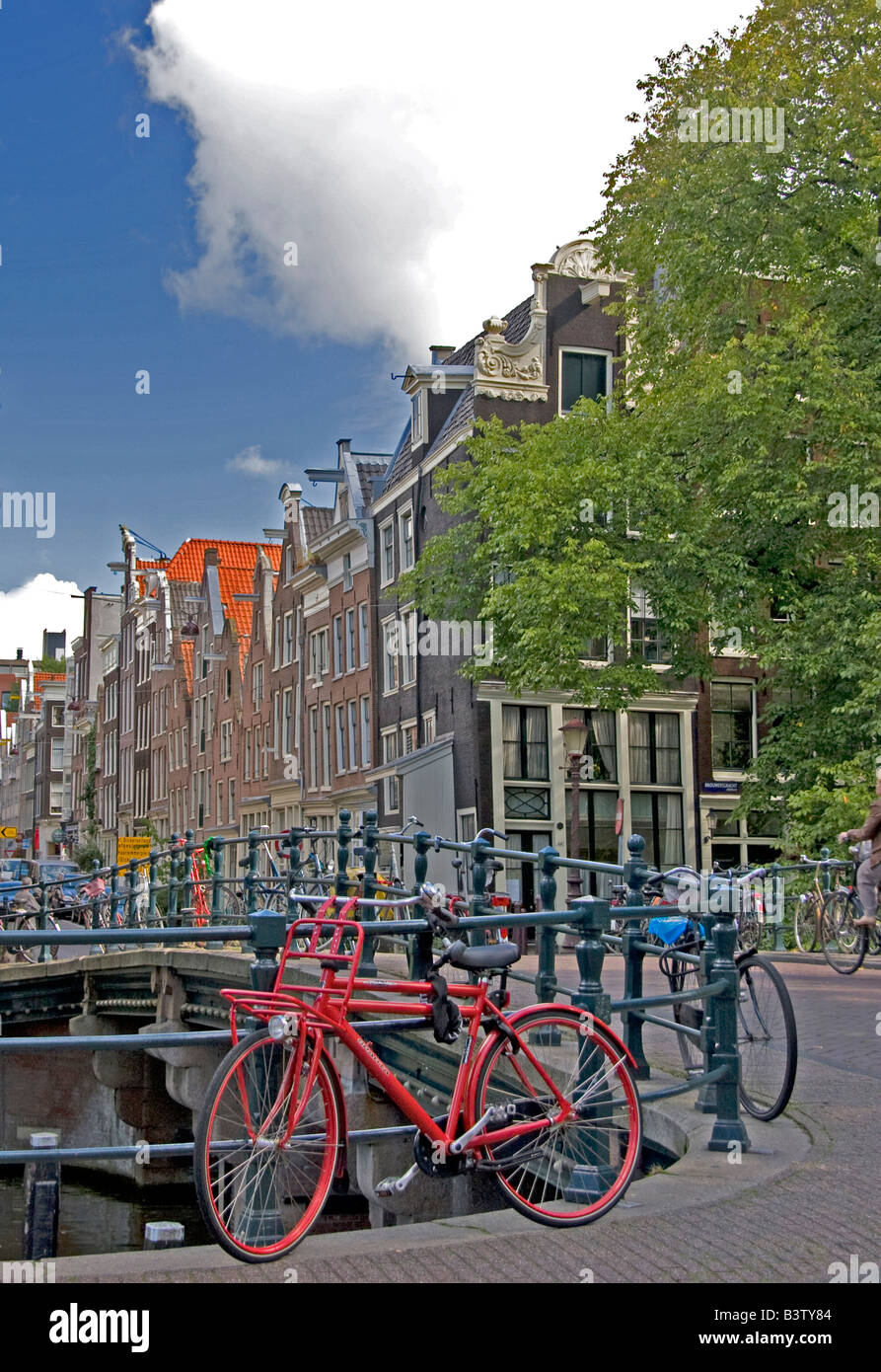 Bright red bike parked along the edge of a canal bridge along with many ...