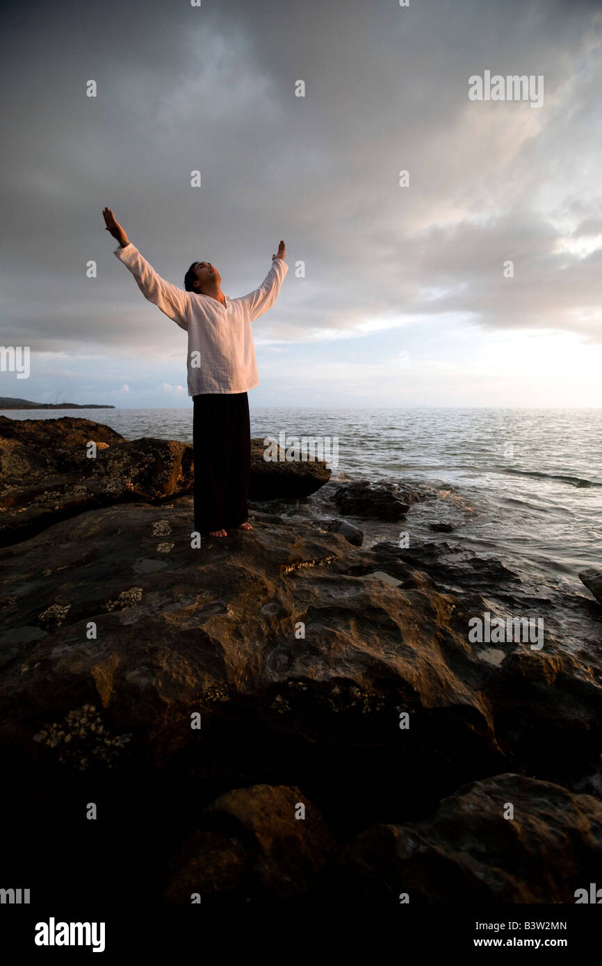 A person with arms raised on a beach at sunset Stock Photo - Alamy