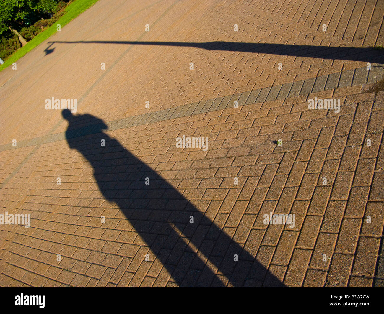 Shadows of the photographer and a light standard lie on brick pavers ...