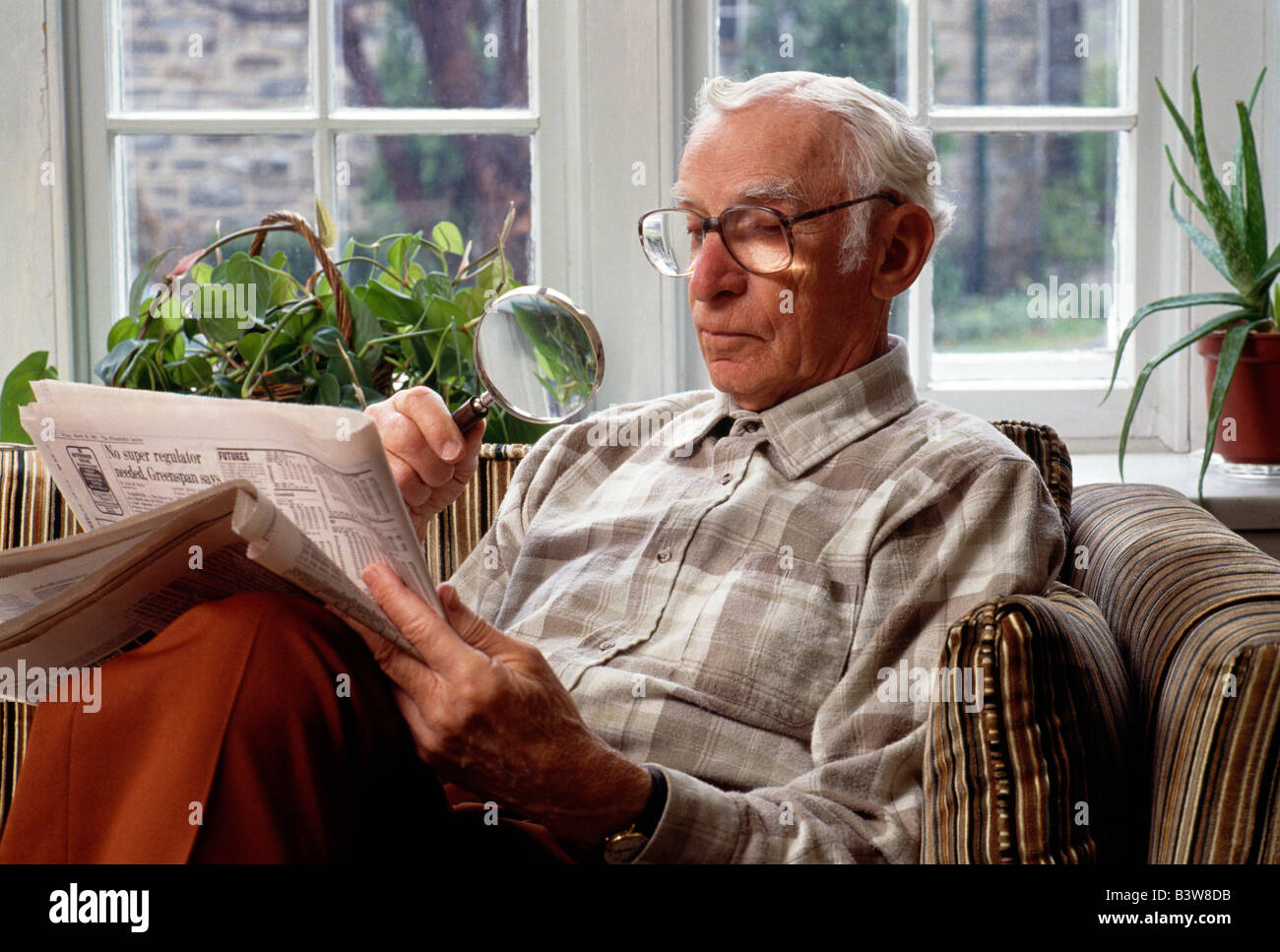 Elderly gentleman reading with a magnifying glass in his home Stock ...