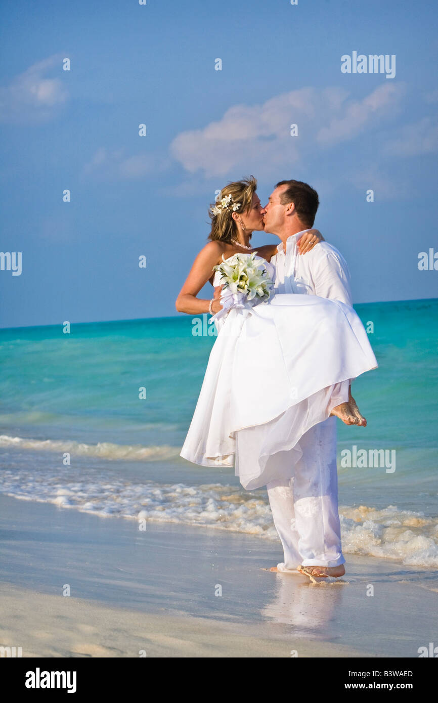 Groom carrying bride on beach Stock Photo - Alamy
