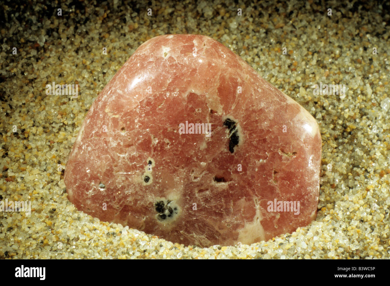 Rhodochrosite, polished pebble on sand Stock Photo - Alamy