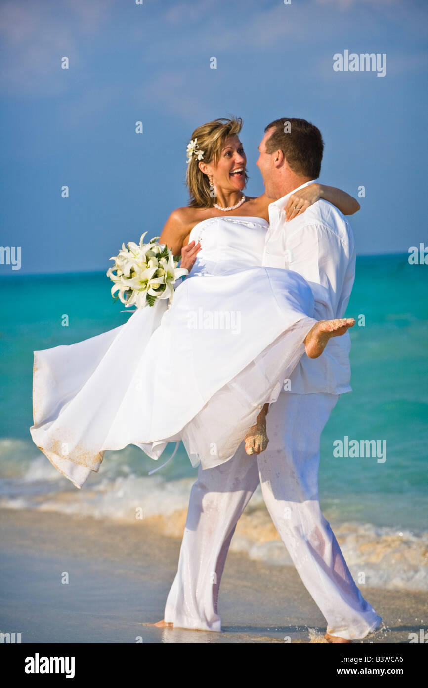 Groom carrying bride on beach Stock Photo - Alamy