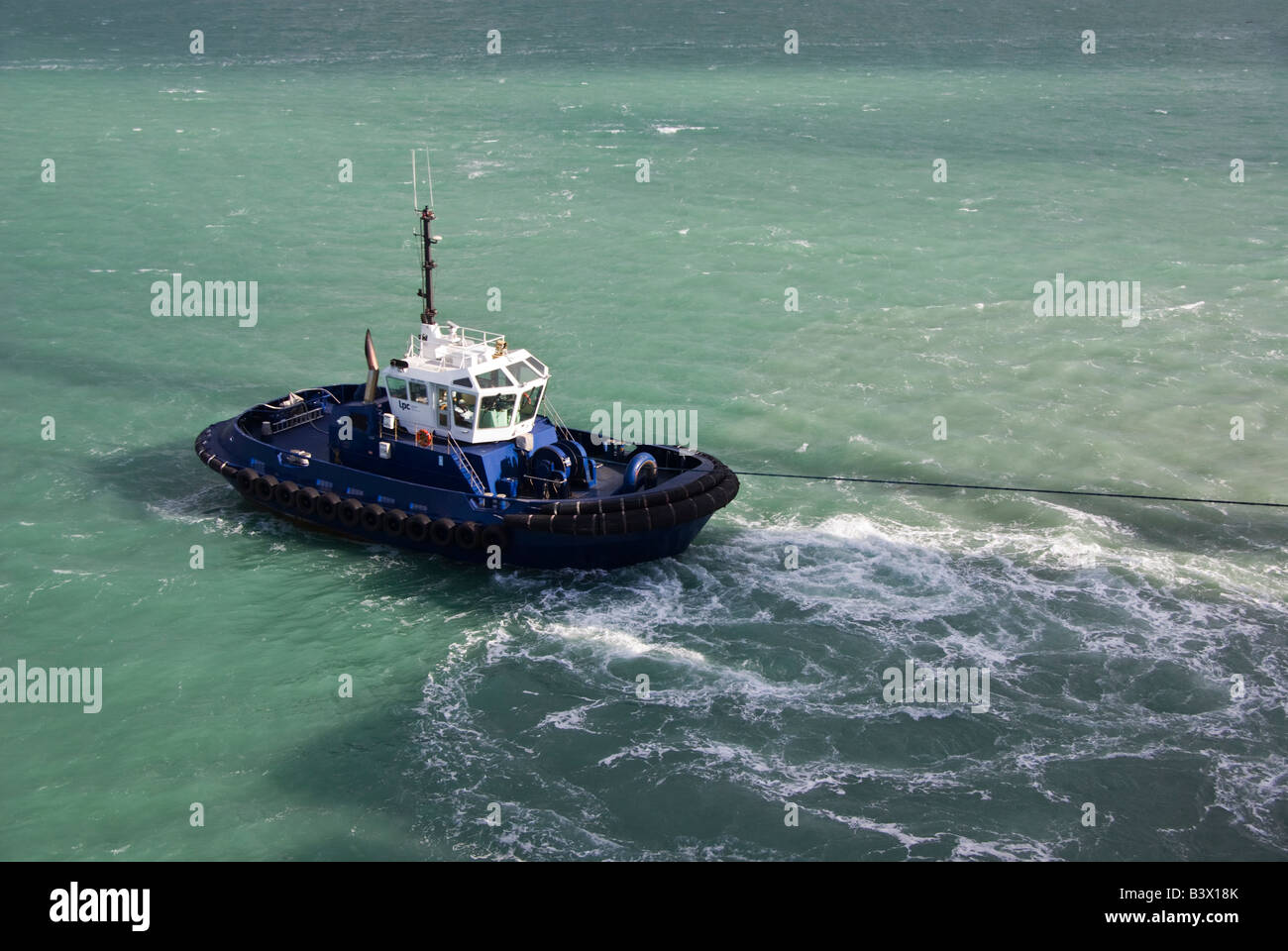 A tug pulls while assisting a ship in port, as seen from the bridge of ...