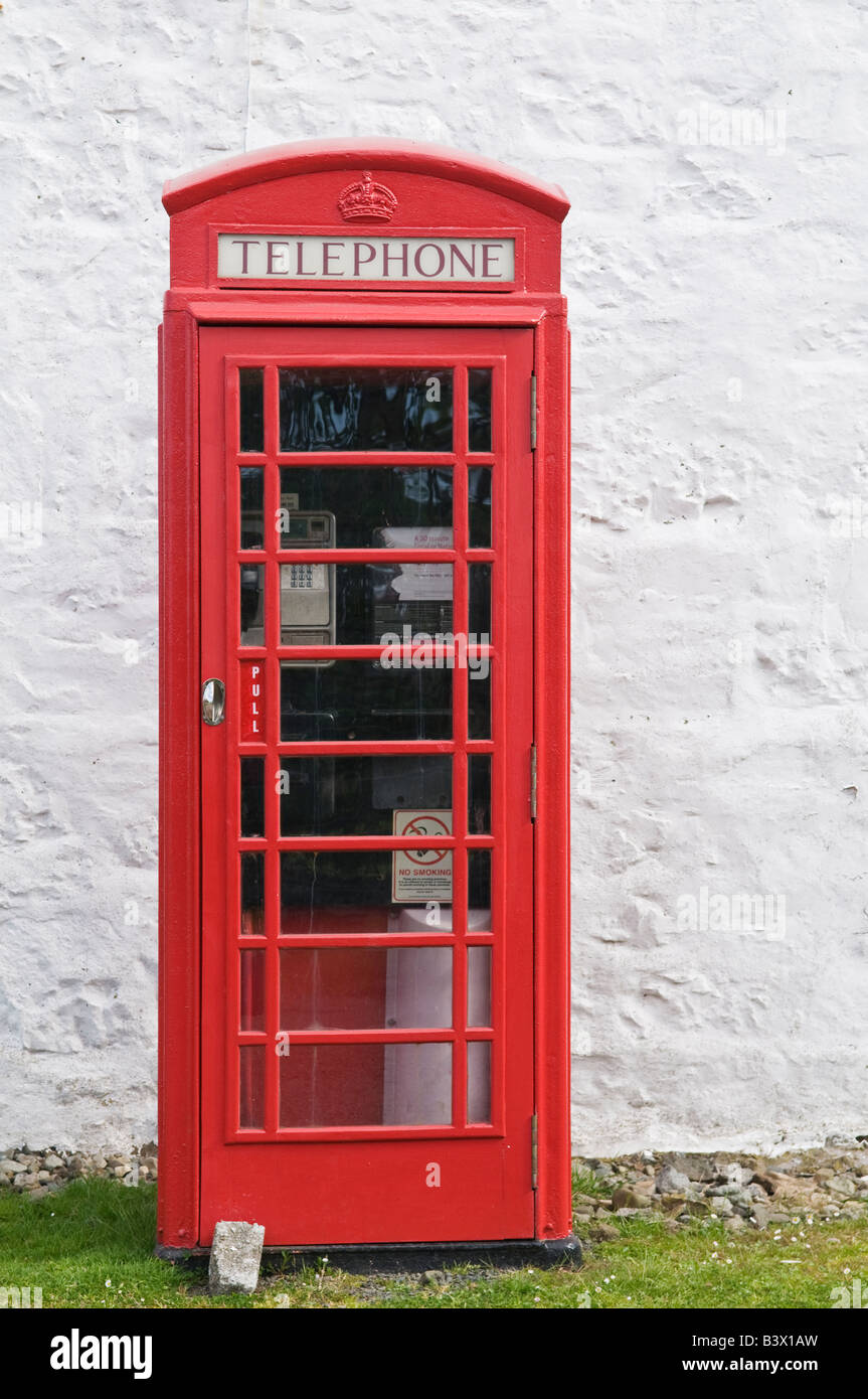 Traditional British red telephone booth next to white stone wall Stock ...