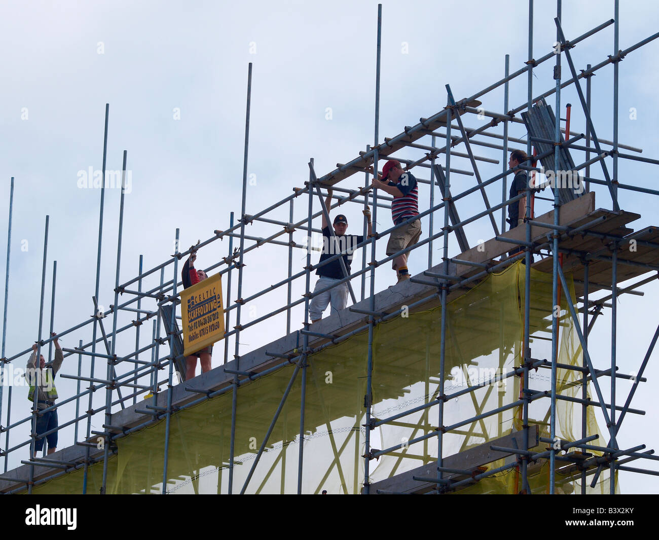 Five Workman dismantling scaffolding from around an old hotel that was ...