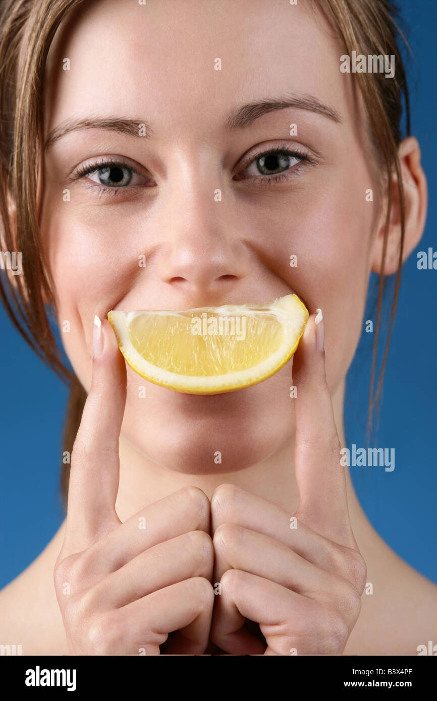 Female model holding a lemon slice over her mouth Stock Photo - Alamy