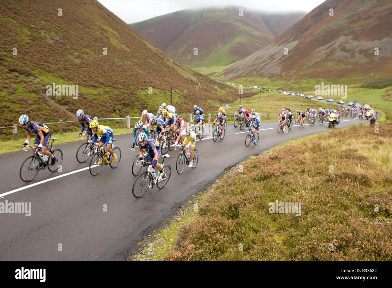 Tour of Britain cycle race peloton climbing up the Mennock Pass misty ...