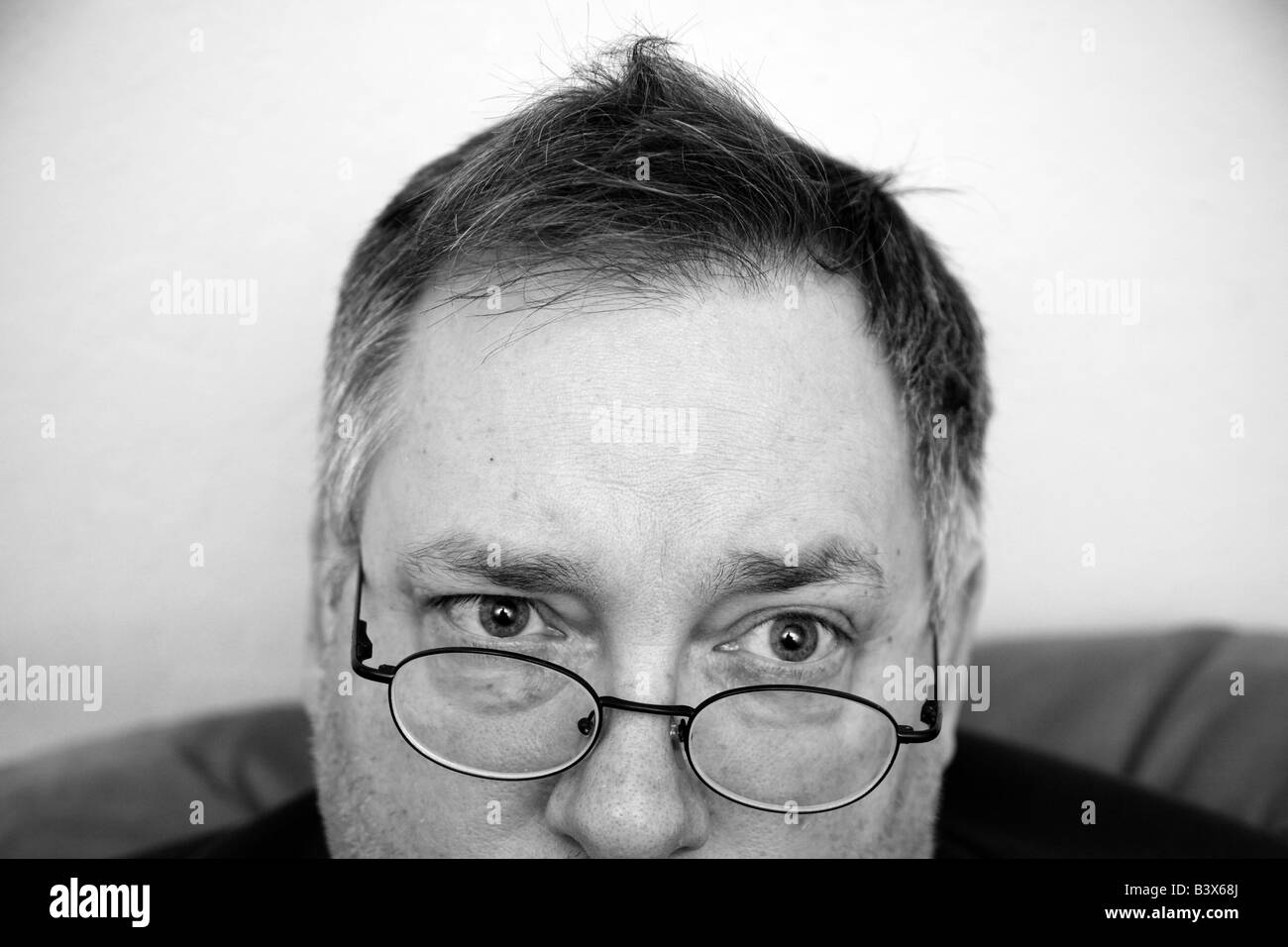 Man quizzically peering over his spectacles Stock Photo - Alamy