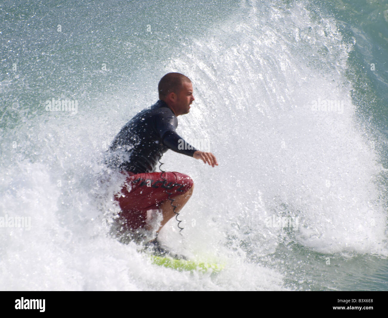 Bodyboarder kneeling on his board as he rides a breaking wave Stock ...