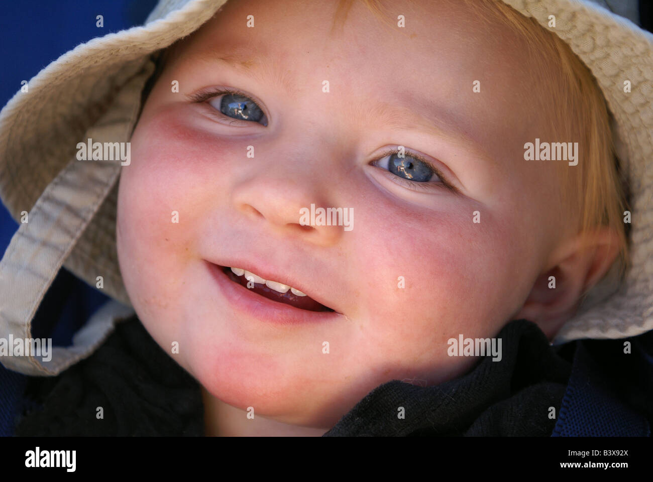 close-up of small girl looking directly into camera and wearing hat ...