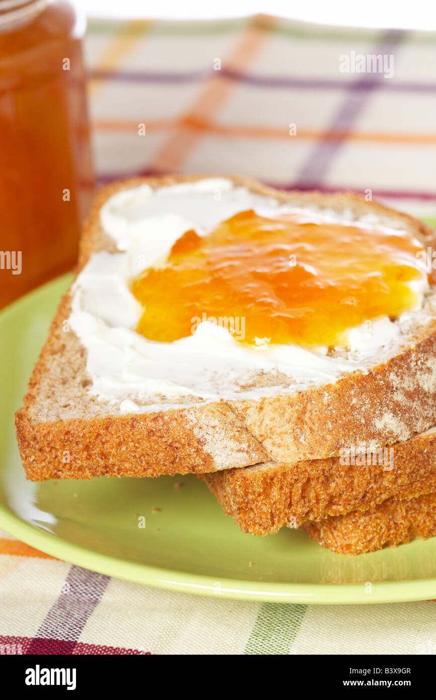 Toast with butter and peach jam glass jar in the green plate with soft ...