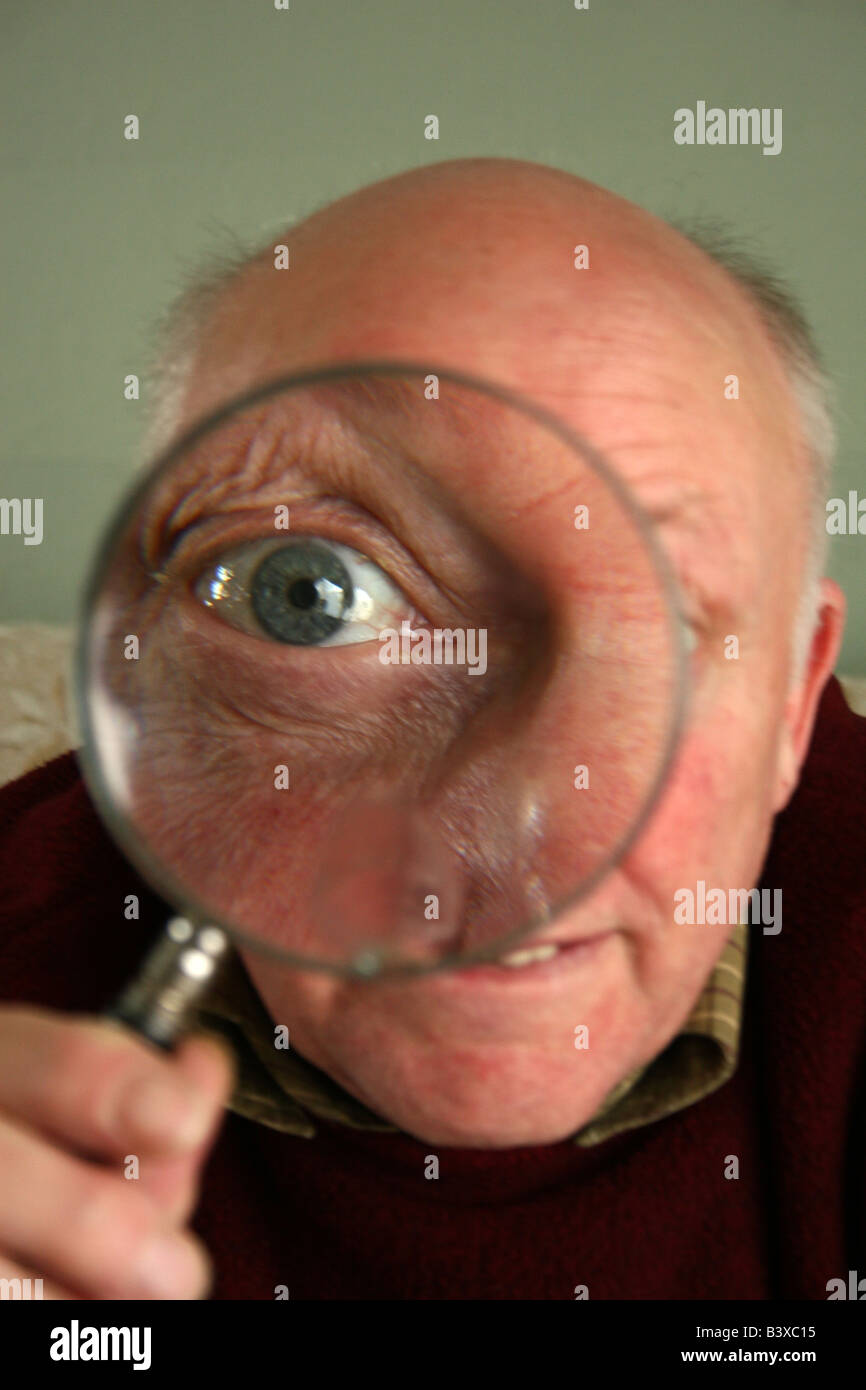 Man looking through a magnifying glass Stock Photo - Alamy