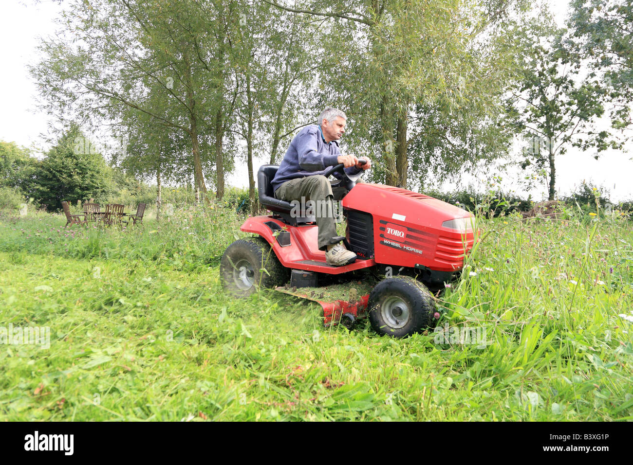 Man mowing a lawn on ride-on mower Stock Photo - Alamy