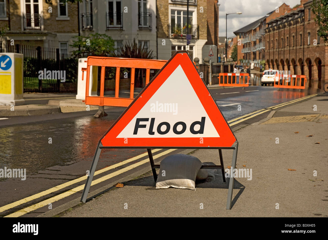 Flood warning sign and barriers across road halting traffic due to ...