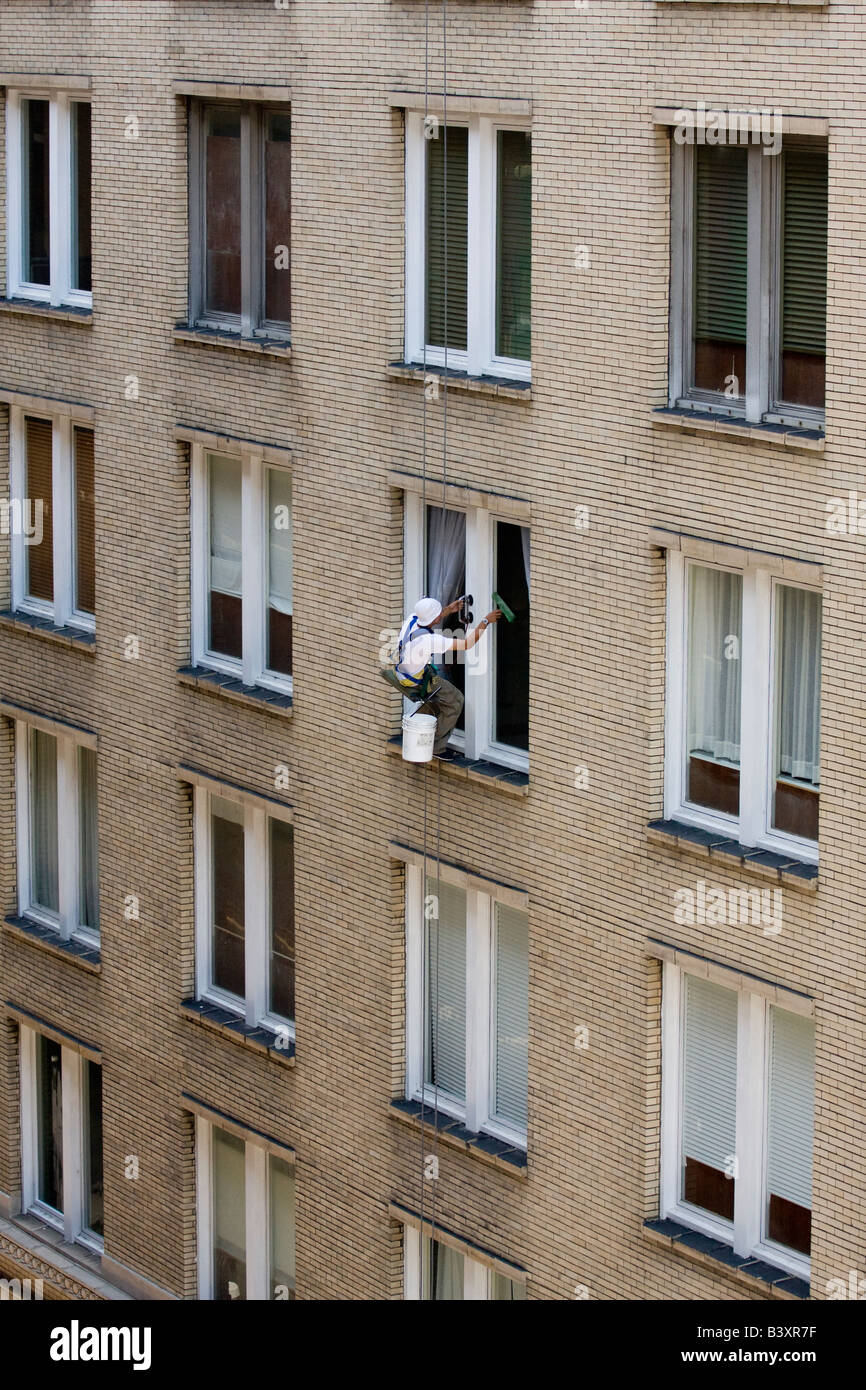 Window washer cleans the windows of a high-rise building several floors ...