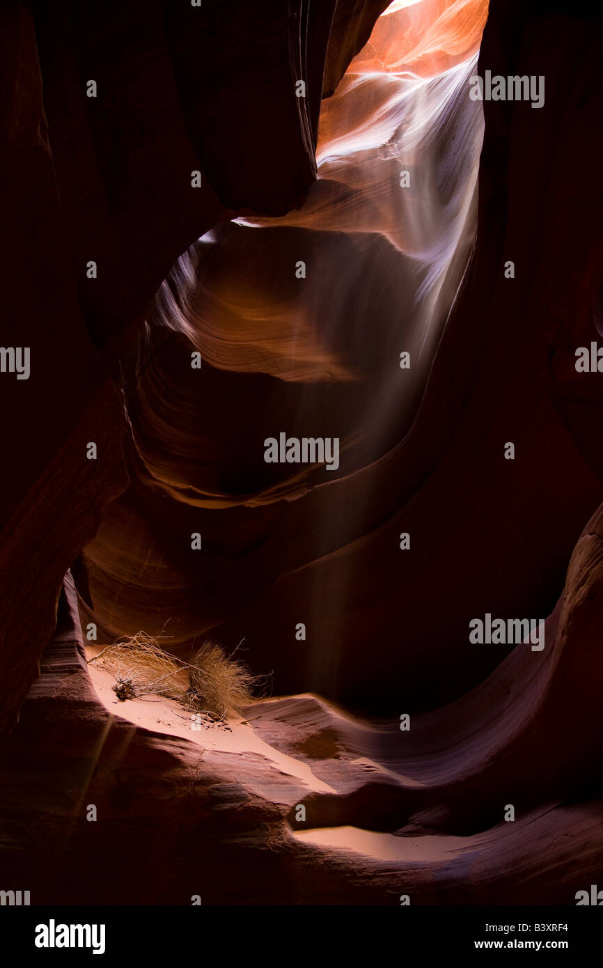 Sunlight highlighting blowing sand falling down red sandstone walls ...