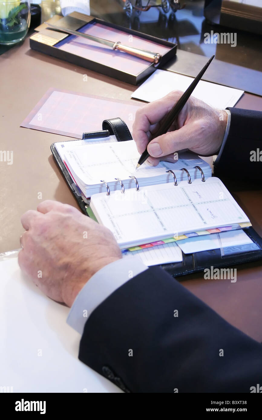Business mans hands writing in day planner at desk Stock Photo - Alamy