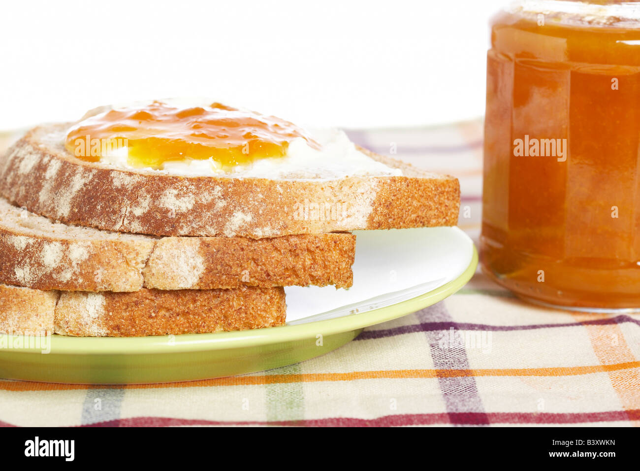 Toast with butter and peach jam glass jar in the green plate with soft ...