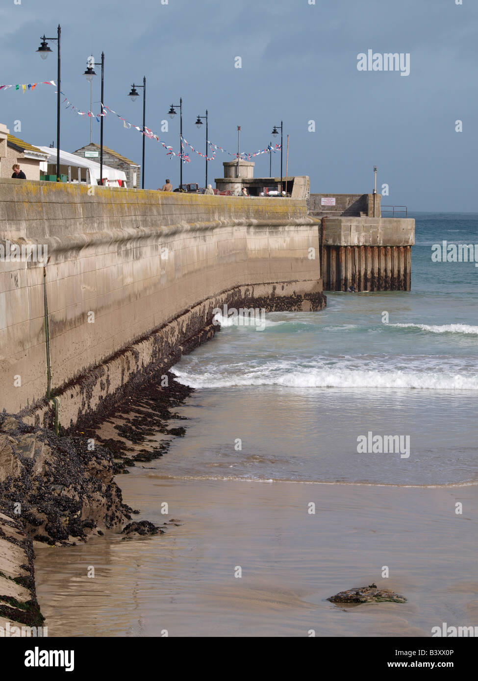 The wall of Newquay Harbour from the beach side as the tide is coming ...
