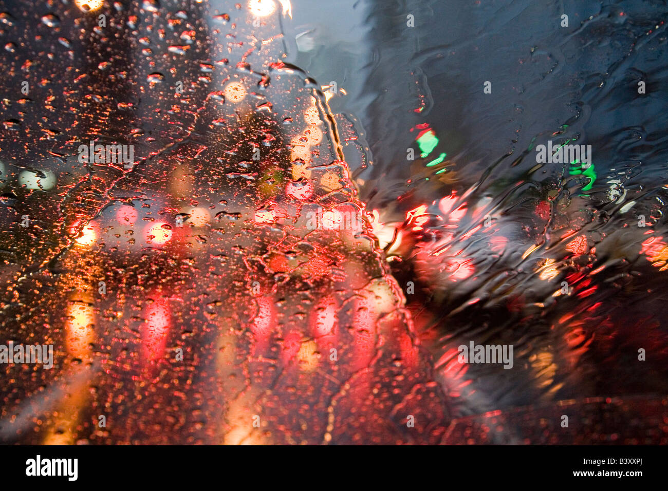 Lights from street cars reflect on a windshield during a rainy day ...