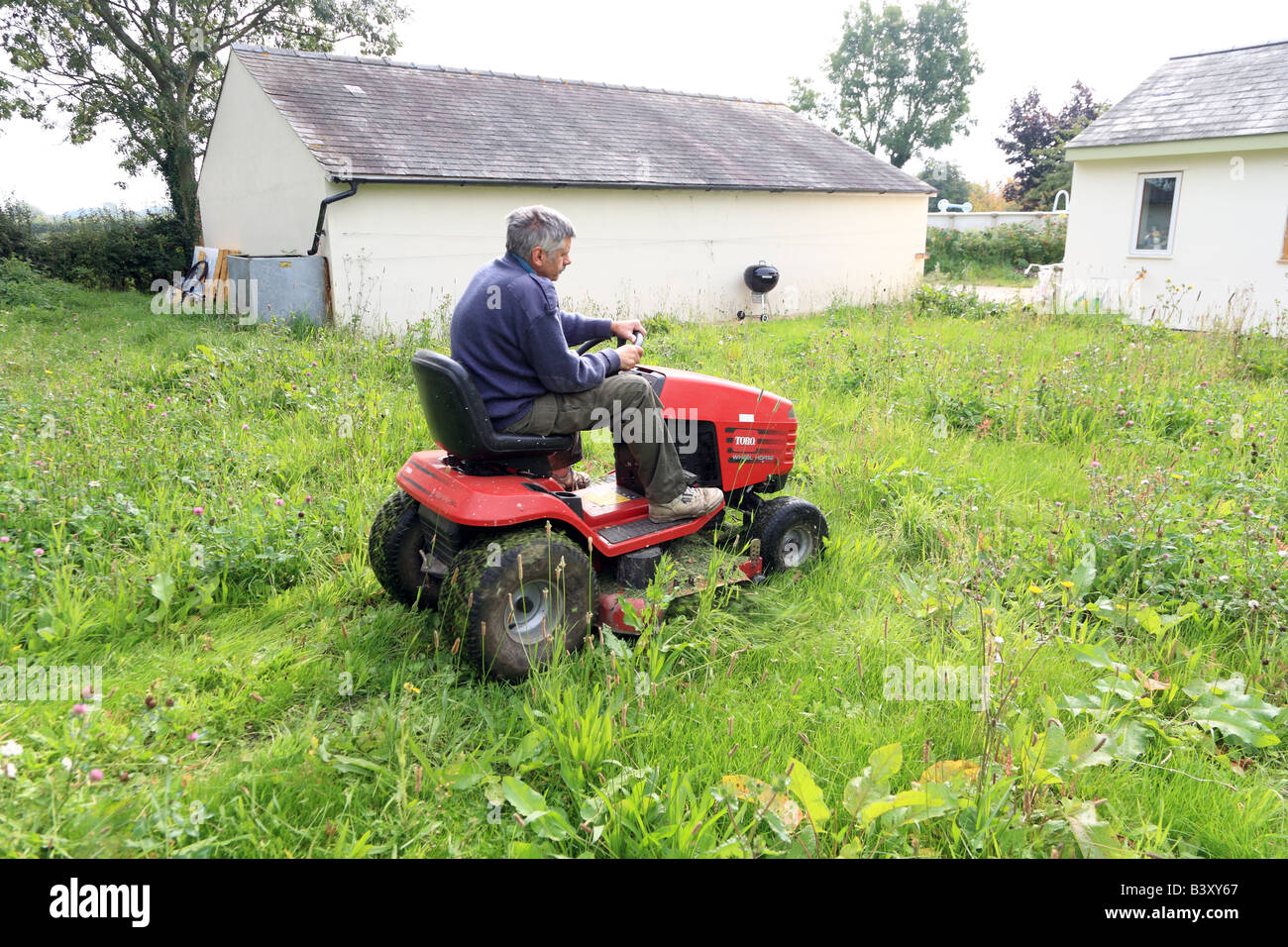 Man mowing a lawn on ride-on mower Stock Photo - Alamy