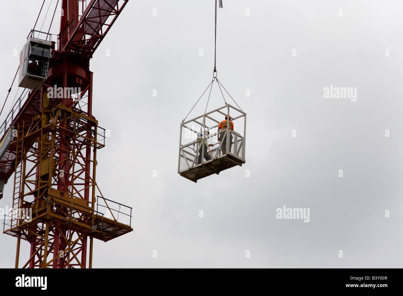 Construction Workers in a first aid cradle, using it inspect a concrete ...