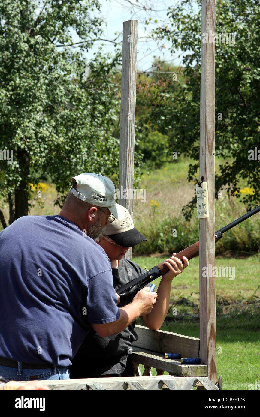A father loading catridges in a rifle for his son at a skeet shooting ...