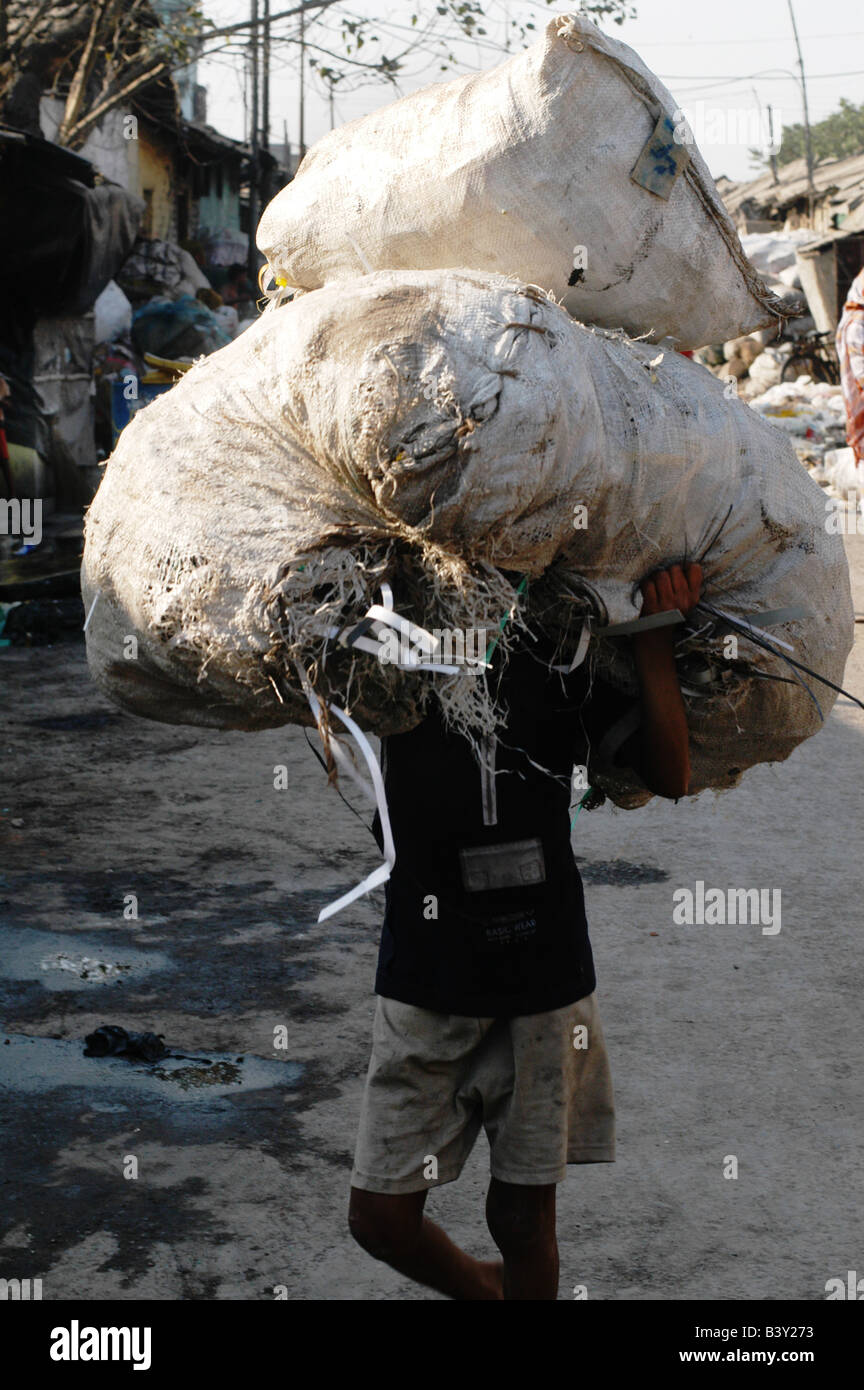 India Kolkata shanty town slum Recycling waste .Boy carrying large sack ...