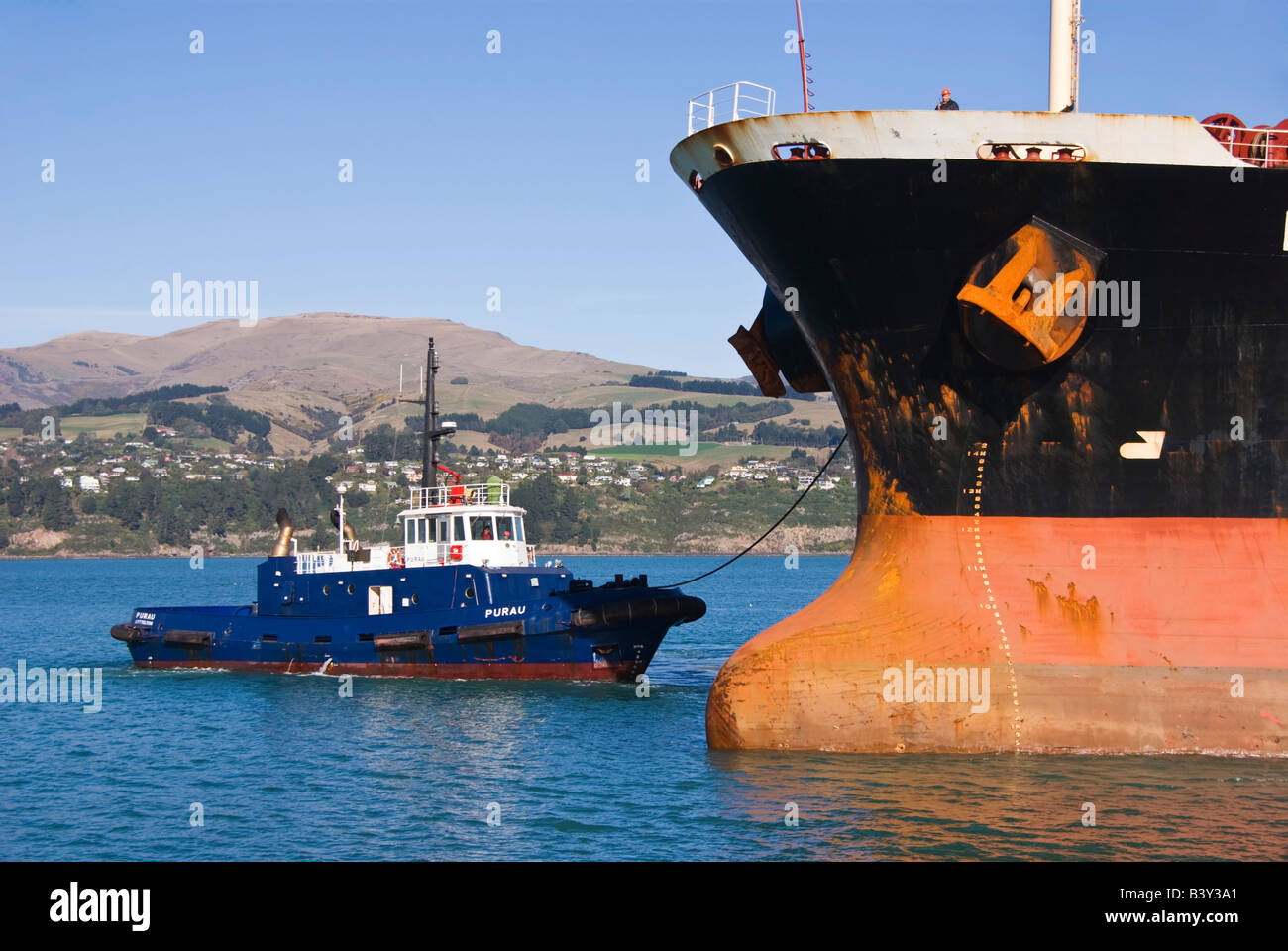 Tug assists at the bow of a ship as it arrives in port Stock Photo - Alamy