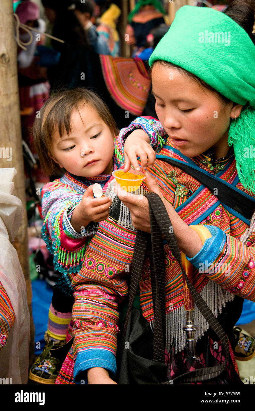A Flower Hmong mother carrying her baby on her back in Sapa market ...
