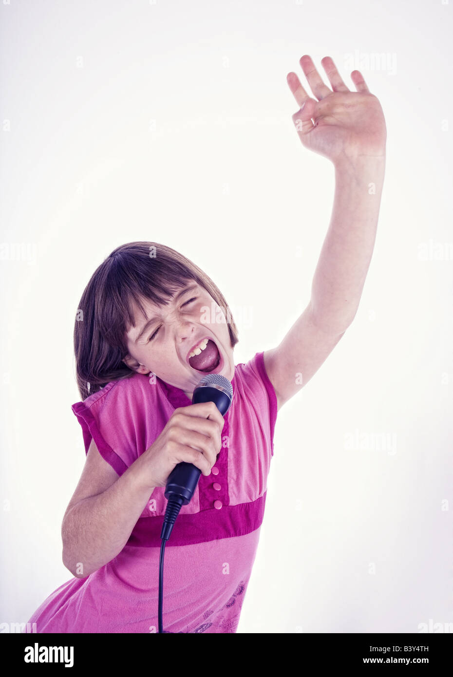 Young girl in pink singing in microphone isolated on white background ...