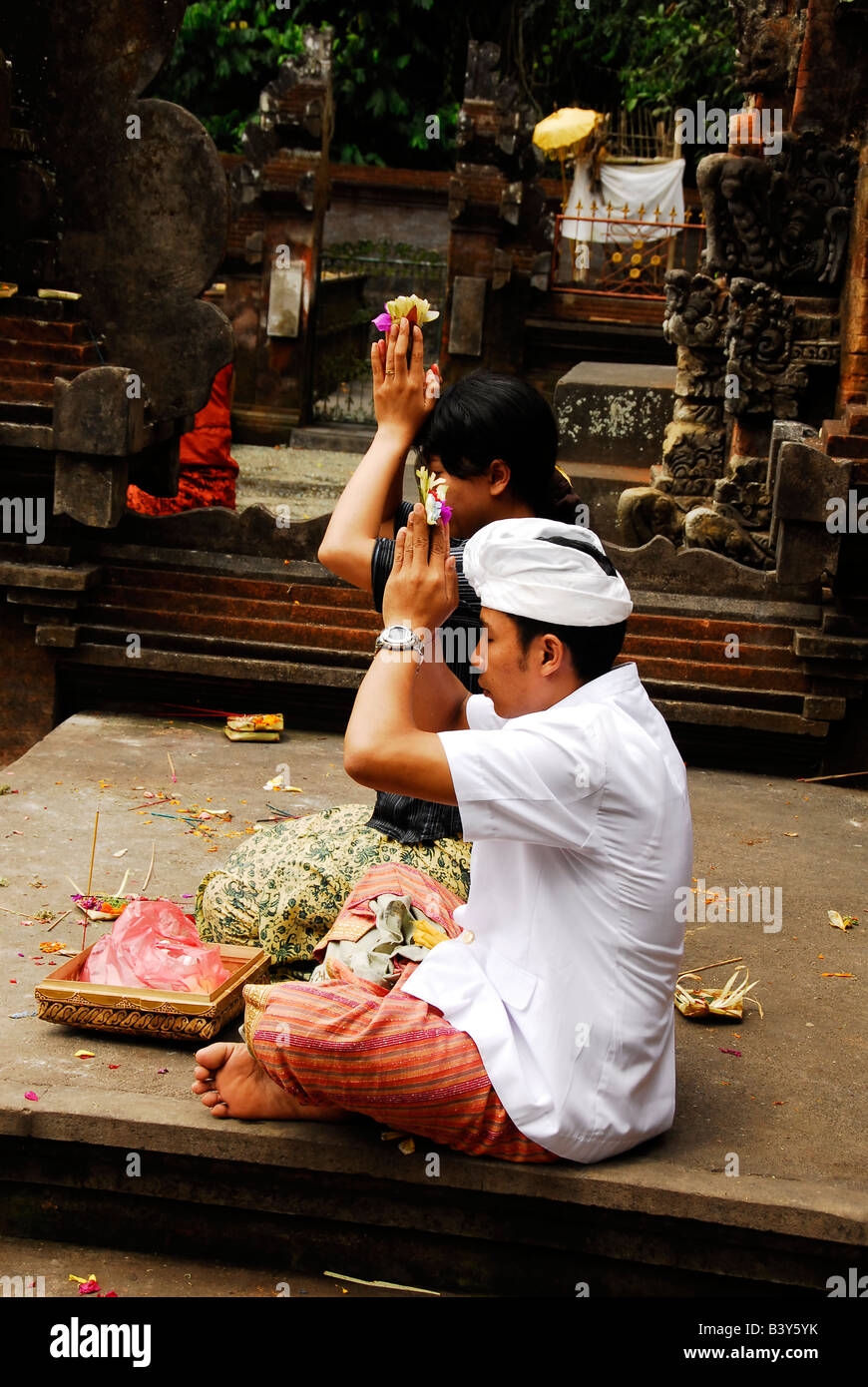 balinese couple praying at family temple , ubud , bali , indonesia ...
