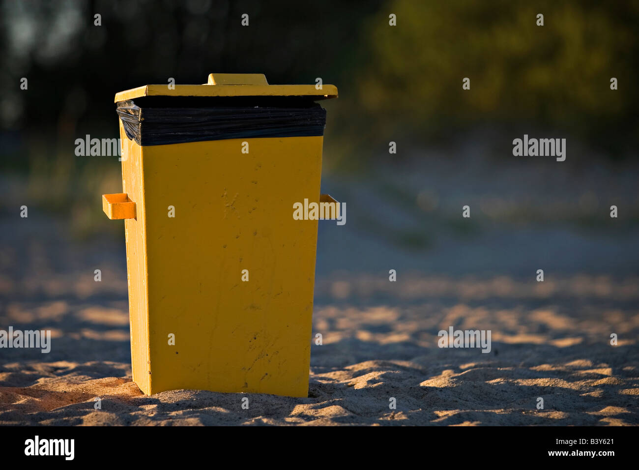 Yellow garbage container in the sand Stock Photo - Alamy