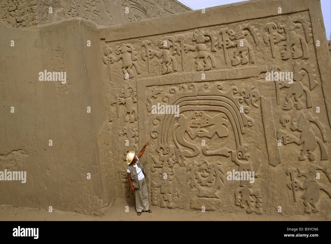 A tour guide explains the bas relief designs carved into the adobe ...