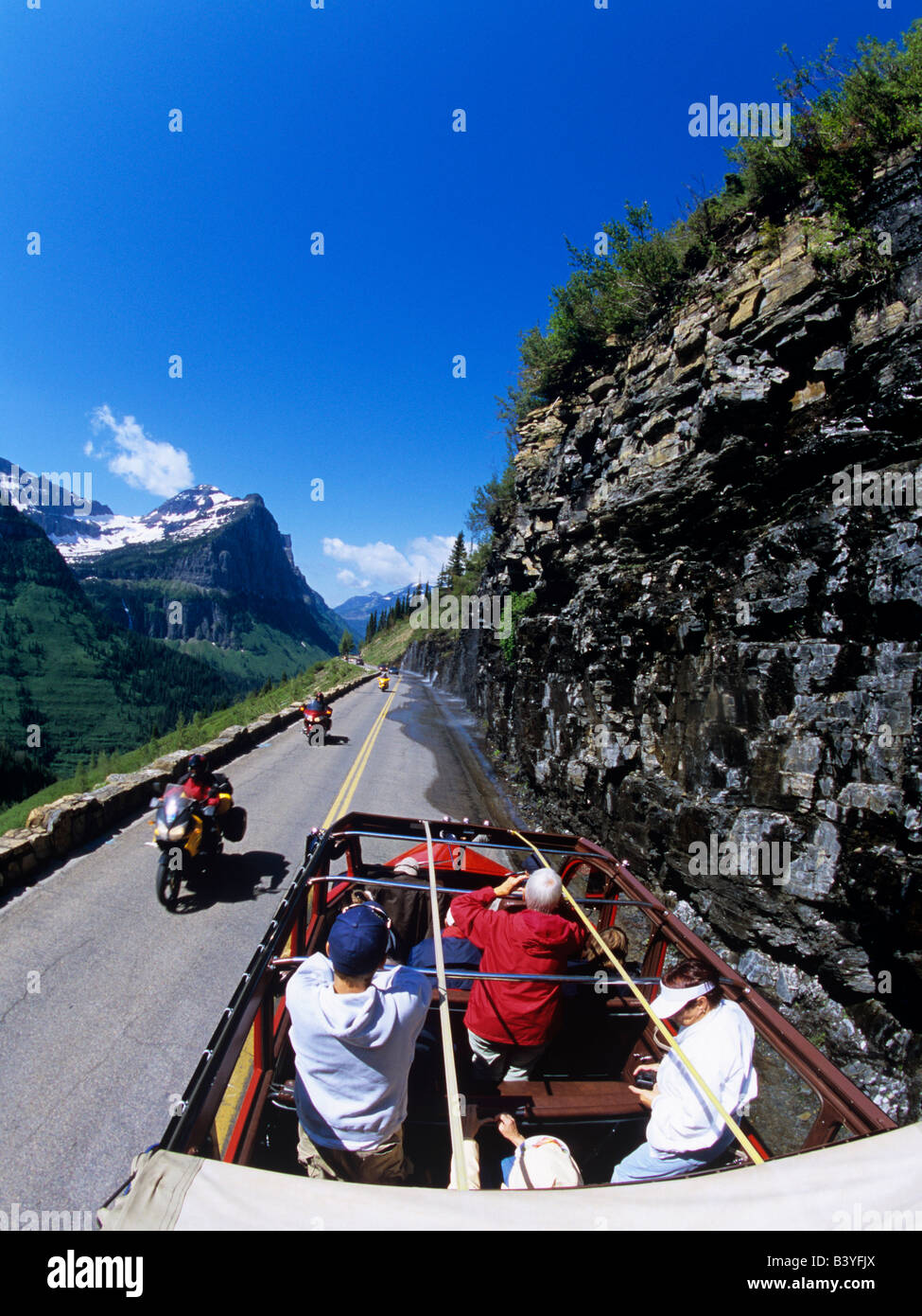 Tourists in the red jammer bus at the Weeping Wall in Glacier National ...