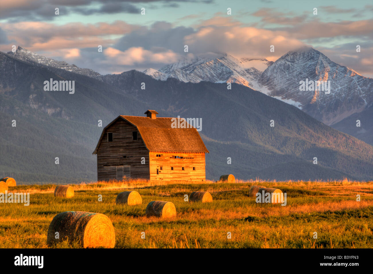 Old barn framed by hay bales and dramatic Mission Mountain Range in ...