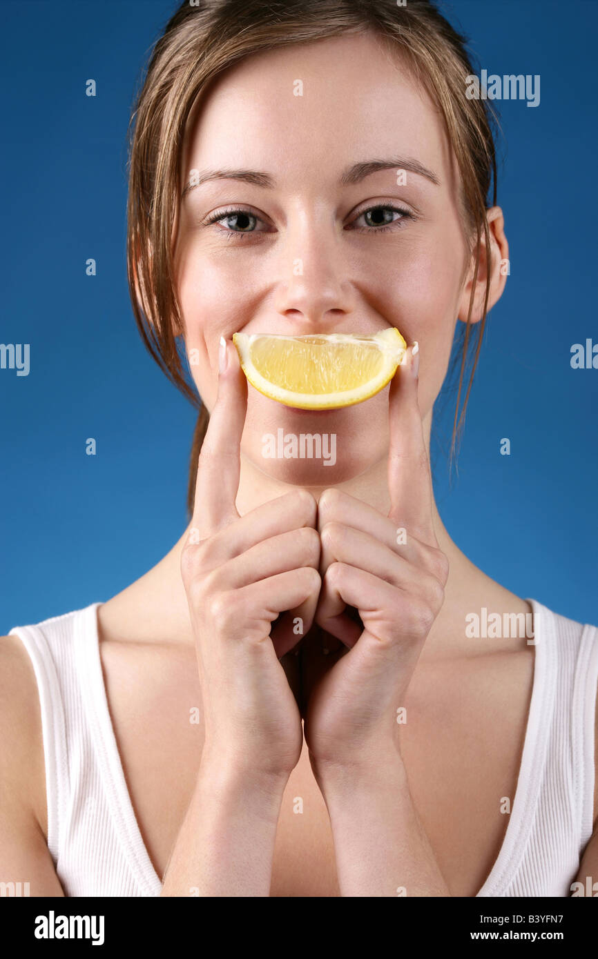 Female model holding a lemon slice over her mouth Stock Photo - Alamy