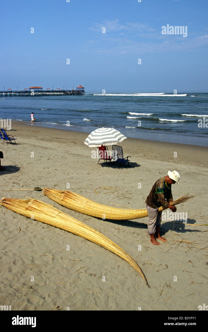 Peru, La Libertad, Huanchaco. A fisherman binds together the totra ...