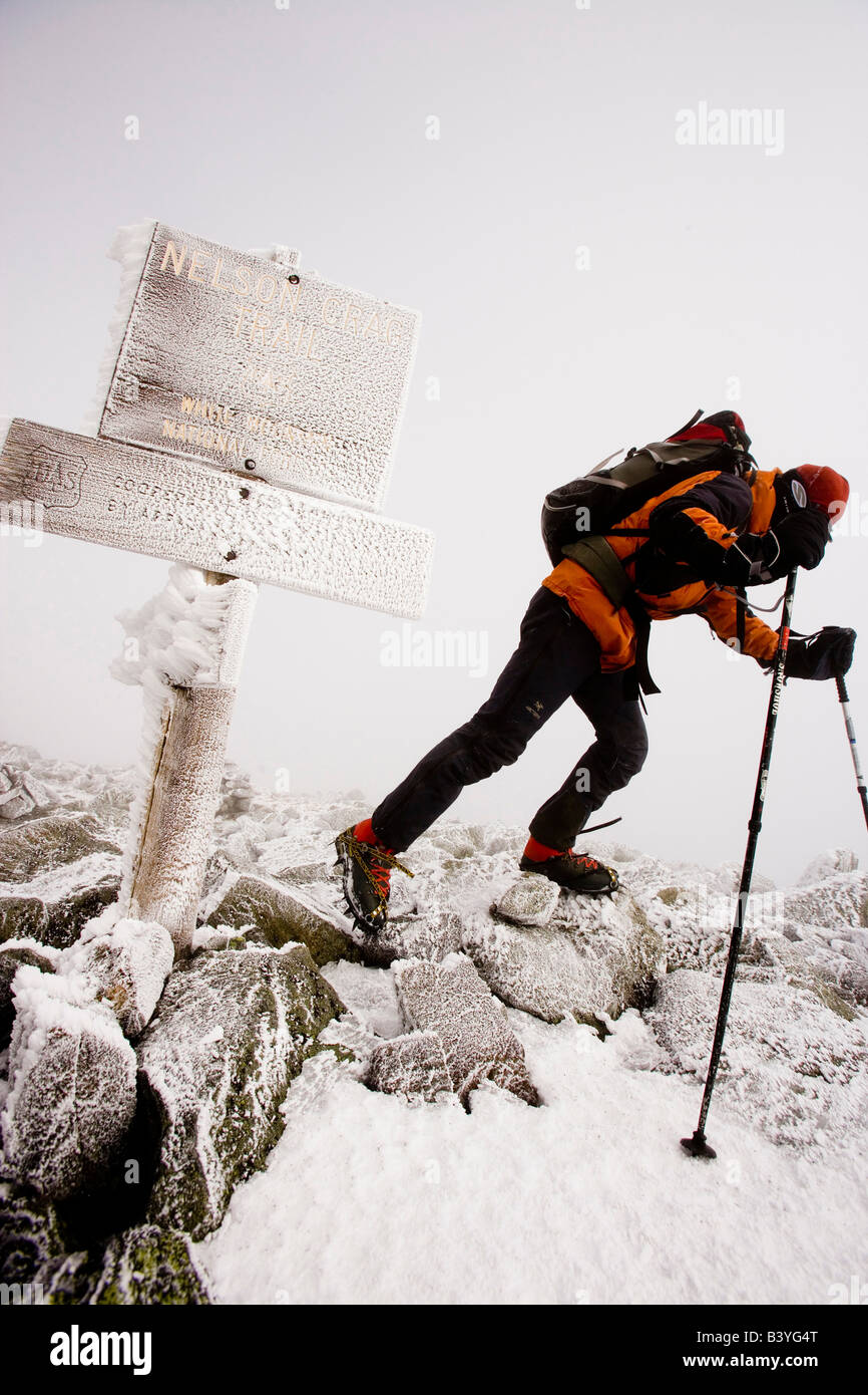 Man winter hiking. Rime ice covers the rocks and a trail sign on Mount ...