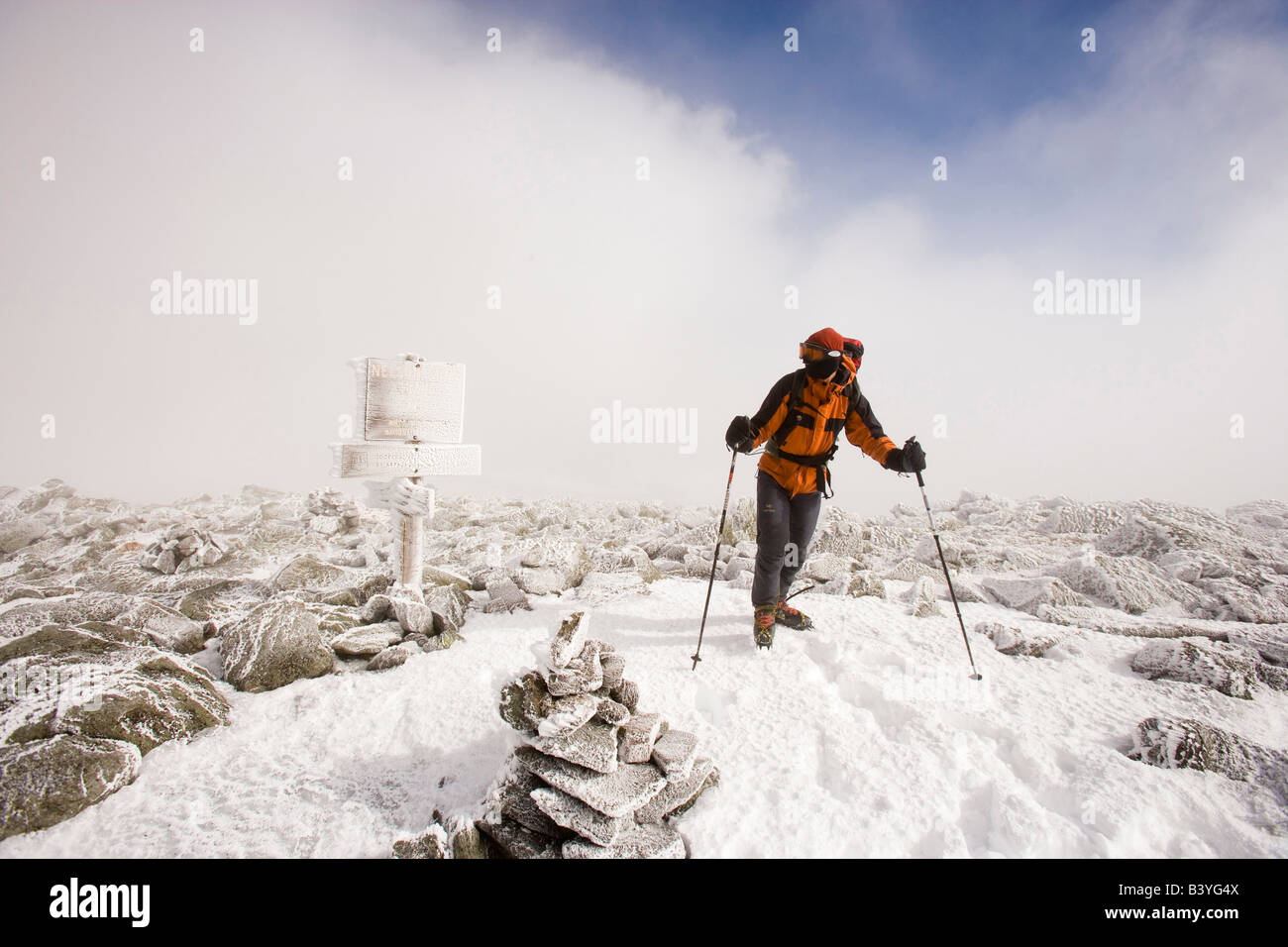 Man winter hiking. Rime ice covers the rocks and a trail sign on Mount ...