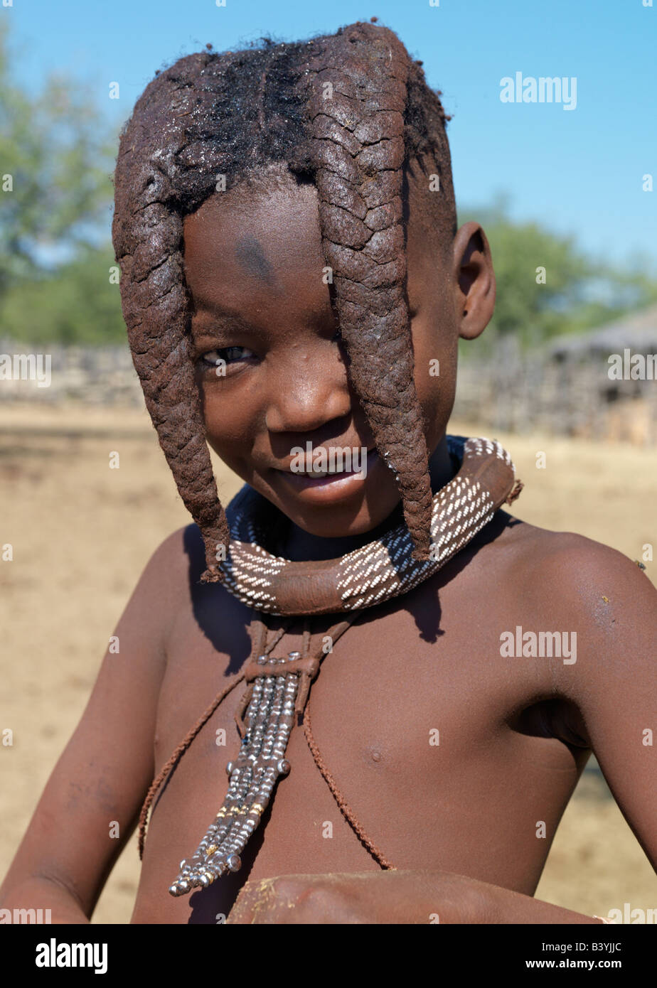 Namibia, Kaokoland. A young girl, her body lightly smeared with a ...