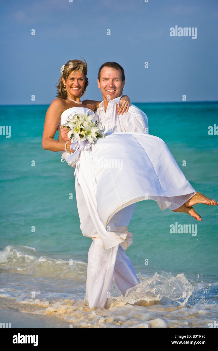 Groom carrying bride on beach Stock Photo - Alamy