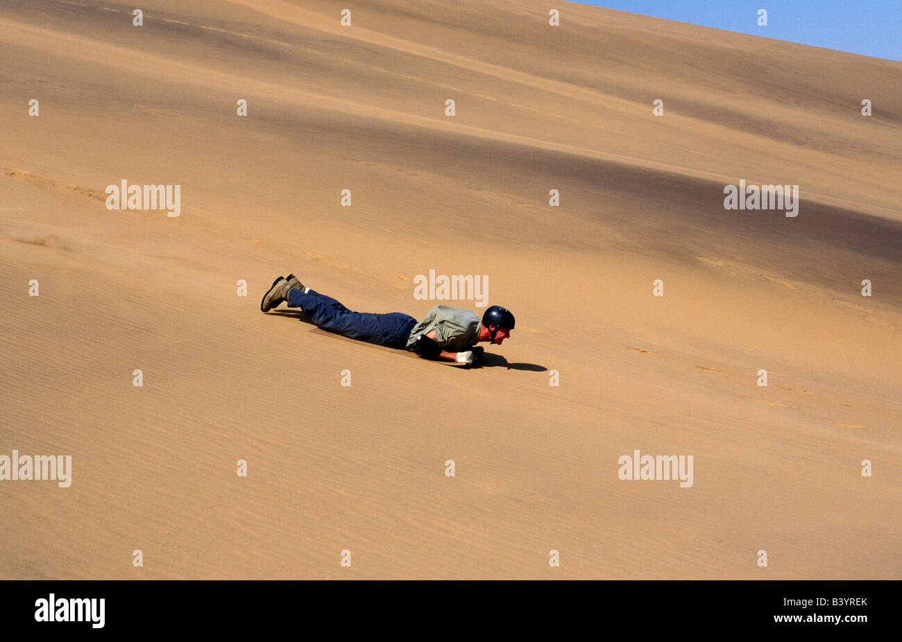 Namibia, Namib Naukluft Park, Swakopmund. Sand boarding on the sand dunes on the outskirts of ...