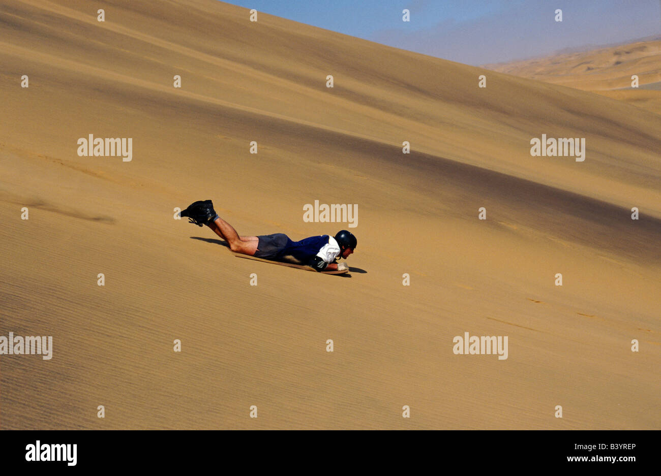 Namibia, Namib Naukluft Park, Swakopmund. Sand boarding on the sand dunes on the outskirts of ...