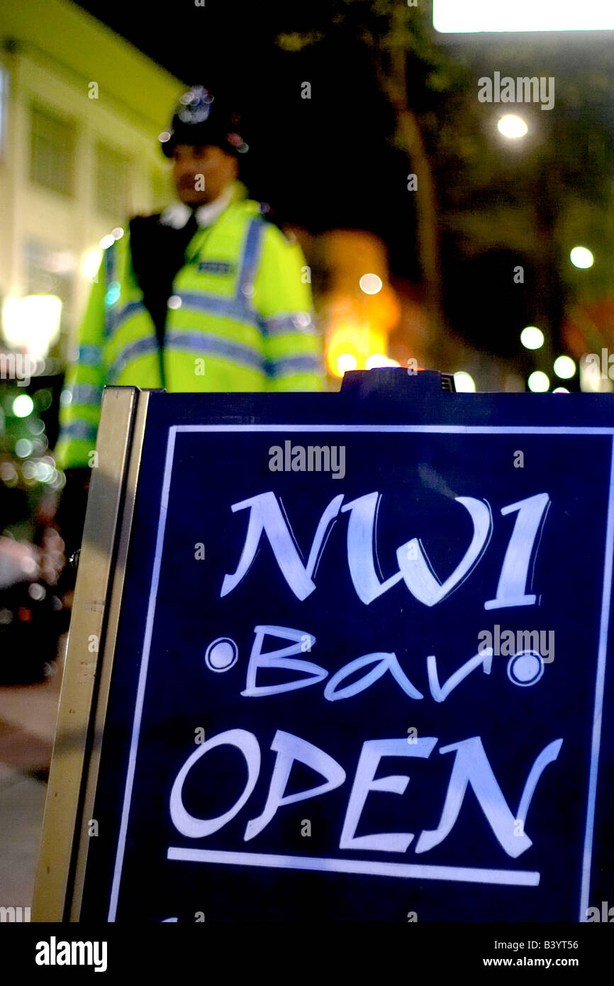 police officer walking past bar open sign NW1 london at night Stock ...