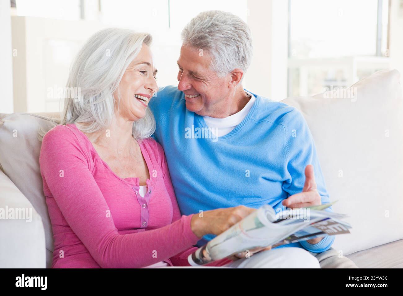 Couple with a magazine smiling Stock Photo - Alamy
