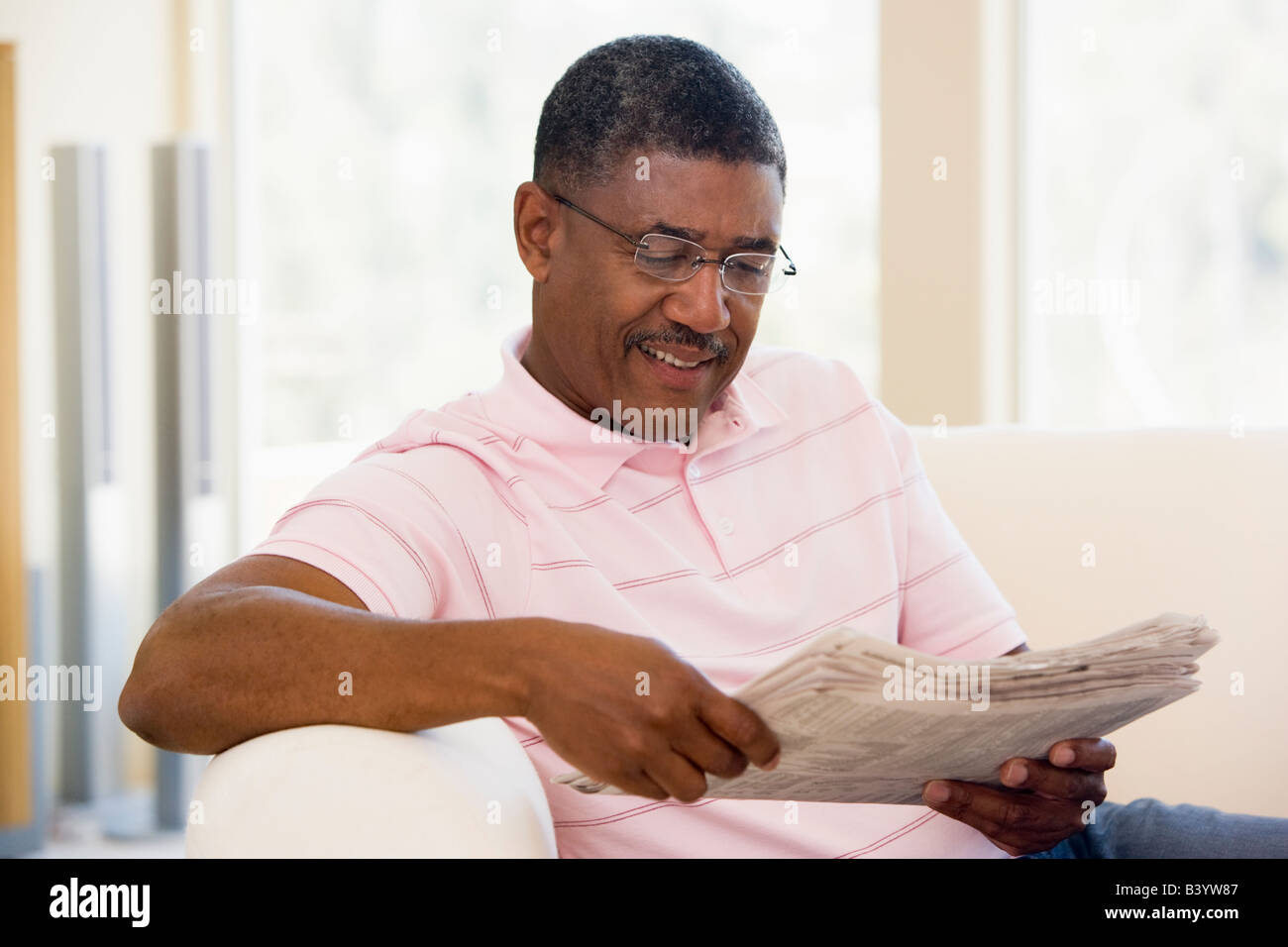 Man relaxing with a newspaper smiling Stock Photo - Alamy