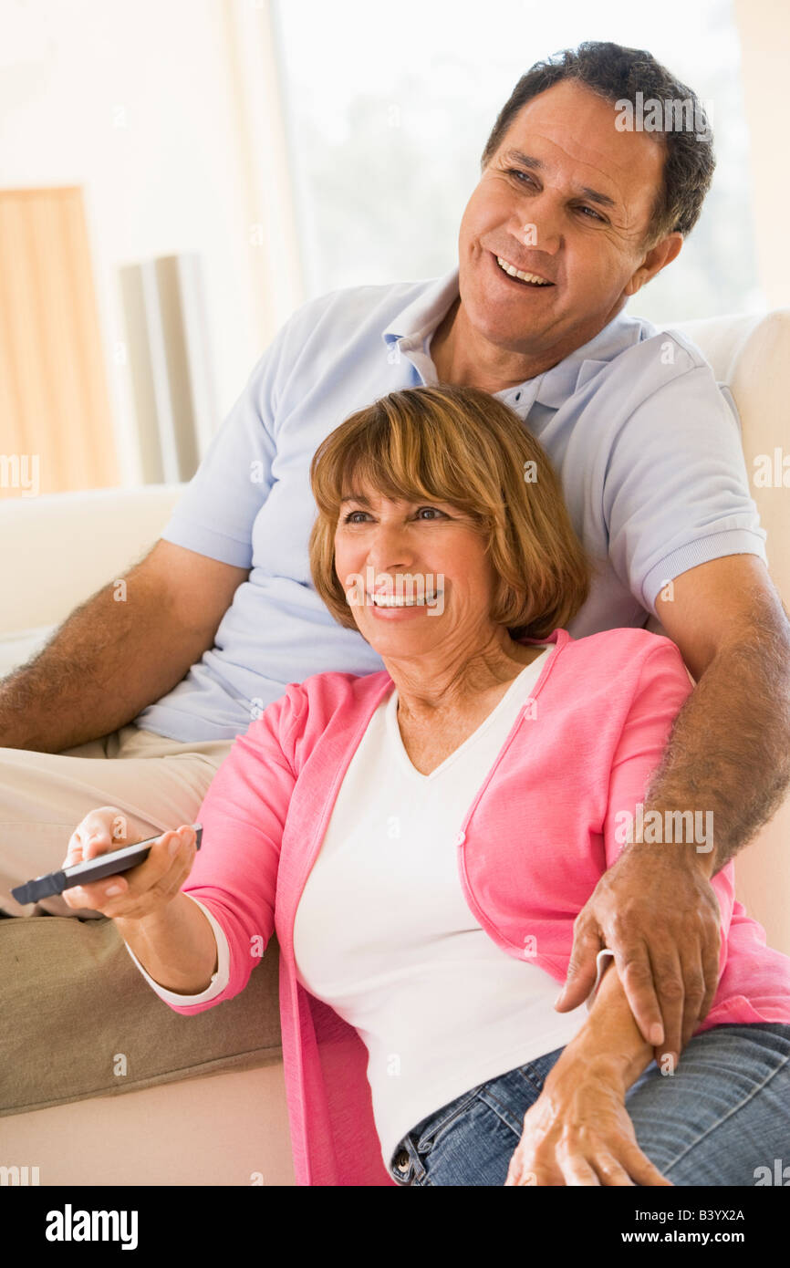 Couple in living room with remote control smiling Stock Photo - Alamy
