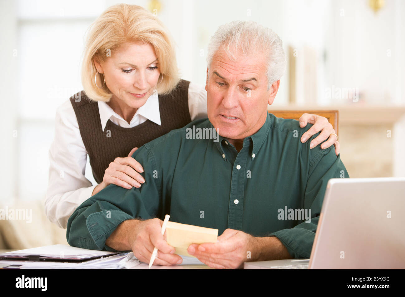 Couple in dining room with laptop and paperwork looking worried Stock ...